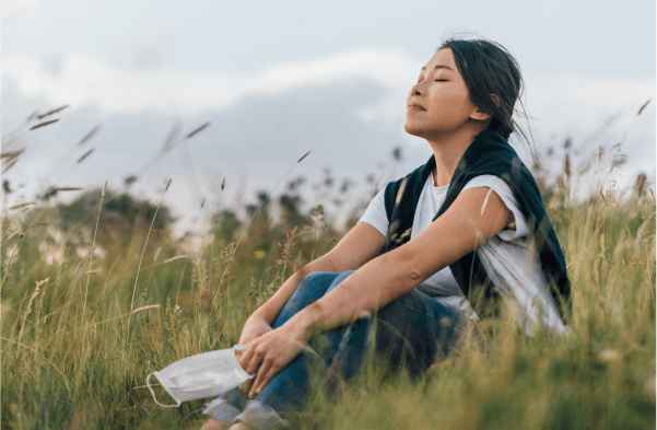 An image of a person closing their eyes in a field